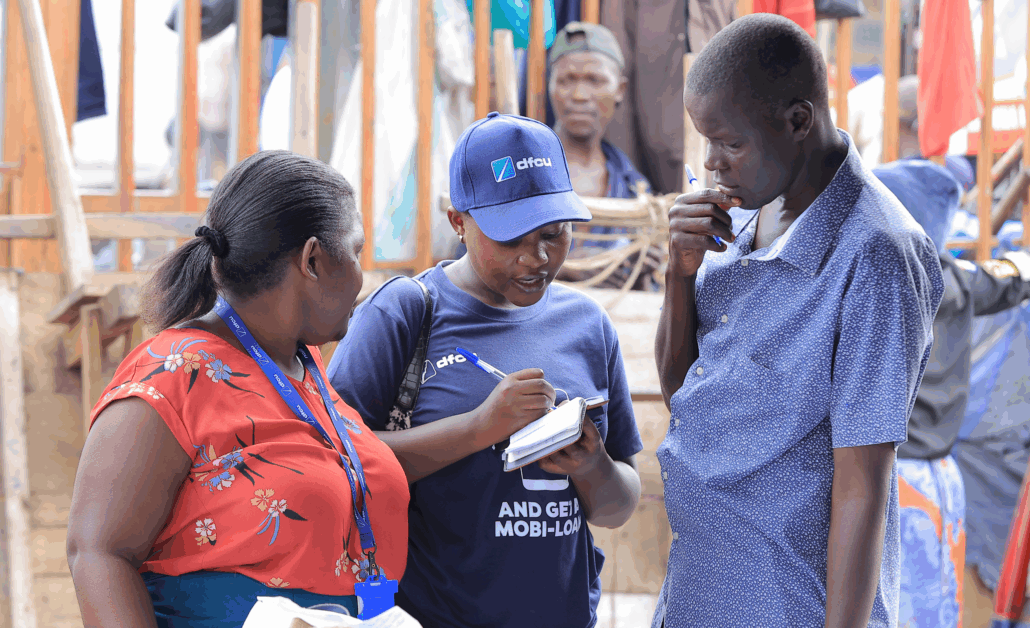 A dfcu Bank Staff member demonstrates to customers in downtown Kampala ...